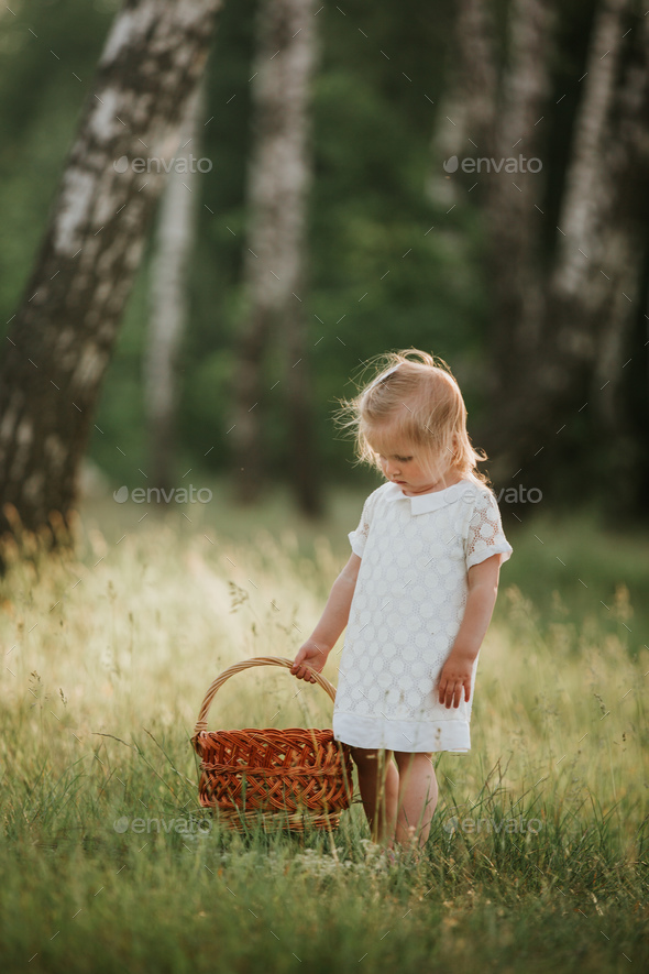 Little girl in white dress with basket enjoying sunny summer day in the ...