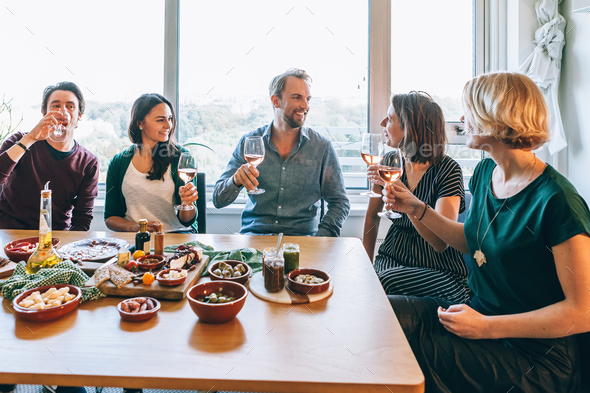 group of friends sitting around a table full of appetizers Stock Photo ...