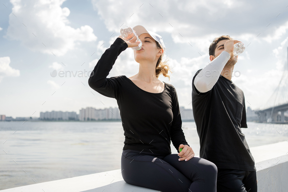 Water is drunk from plastic bottles. Fitness male and female runner ...