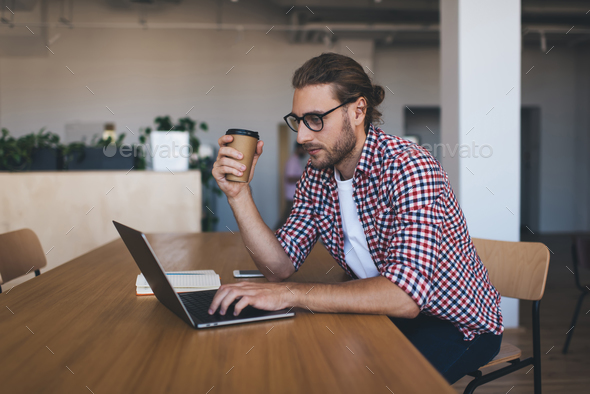 Millennial programmer in classic eyeglasses watching received video on ...