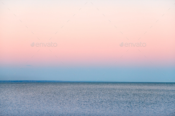 Atmospheric romantic pink red sea sunset sky above blue quiet water ...