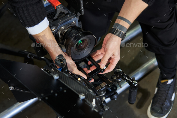 male hands of a cameraman adjust the body kit of a professional movie ...