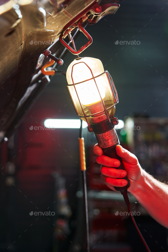 The hand of a caucasian man hangs a lamp carrying lamp by a hook on a ...