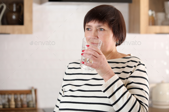 Smiling healthy thirsty fit mid aged 50s woman drinking water. Happy ...