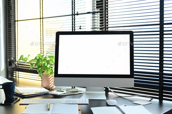 Modern corporate office interior with blank computer monitor, documents ...