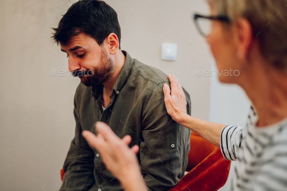 Sad young man talking about his mental health on a group therapy ...