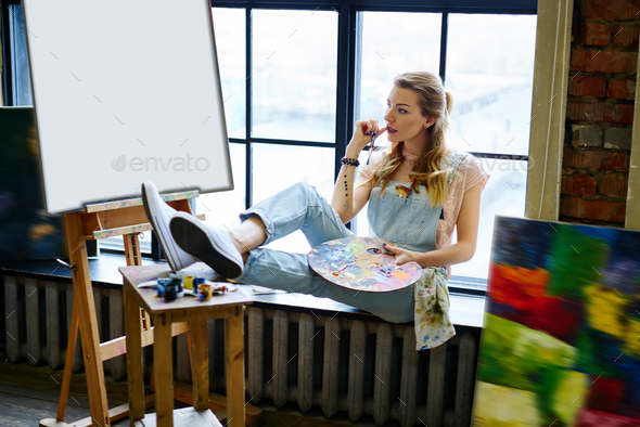 Contemplative female artist with palette for mixing oil dye during ...