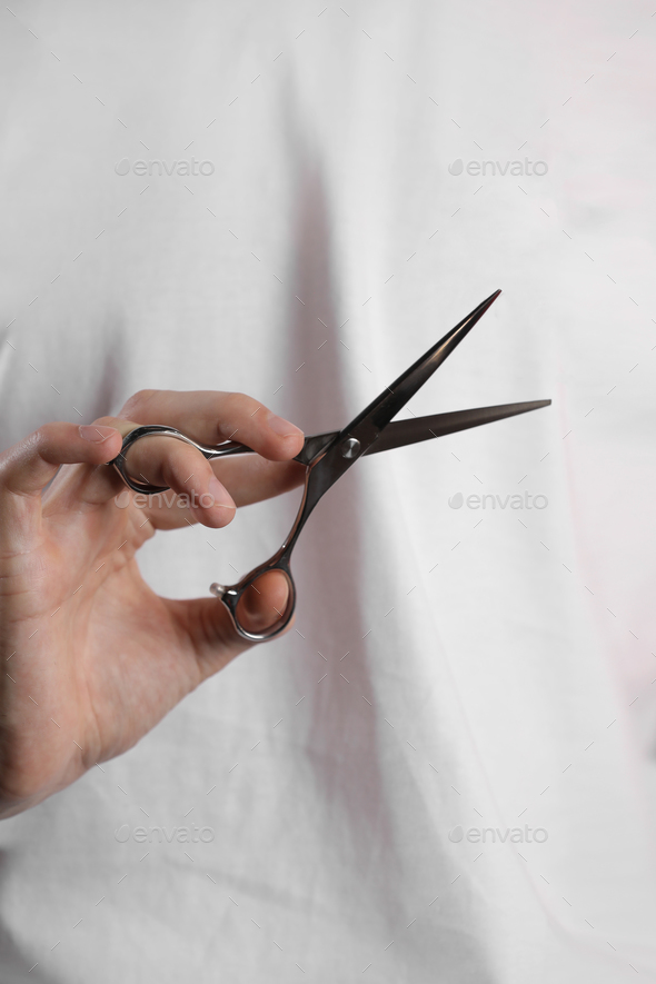 Barber in white t shirt holding scissors, background is blurred ...