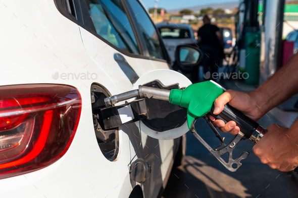 Man with the gun refueling gasoline or diesel fuel in a white car ...