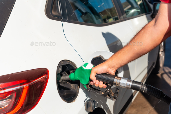 Hand of a man with the gun refueling gasoline or diesel fuel in a white ...