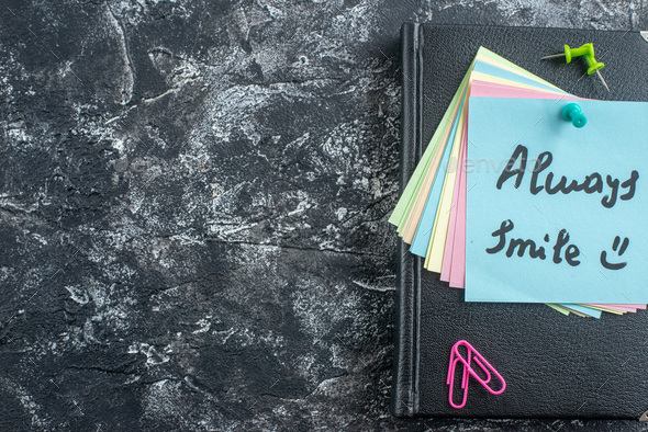 top view always smile note with black copybook on gray background ...