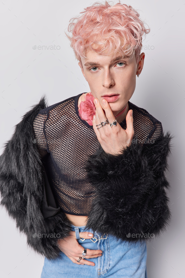 Young transgender man touches face looks seriously at camera wears net ...