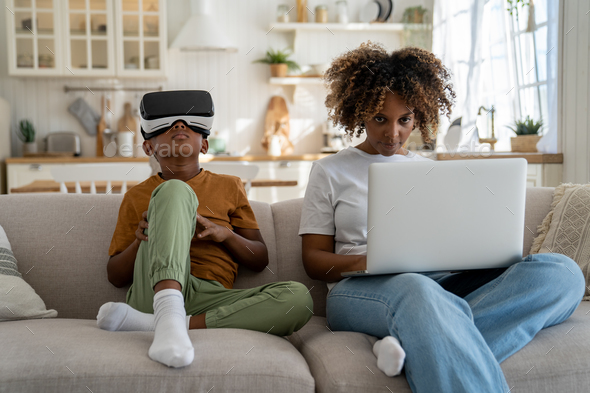 Child using virtual reality simulator headset while sitting on sofa ...