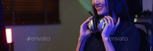 Female cyber hacker gamer in headphone around neck watching video games ...