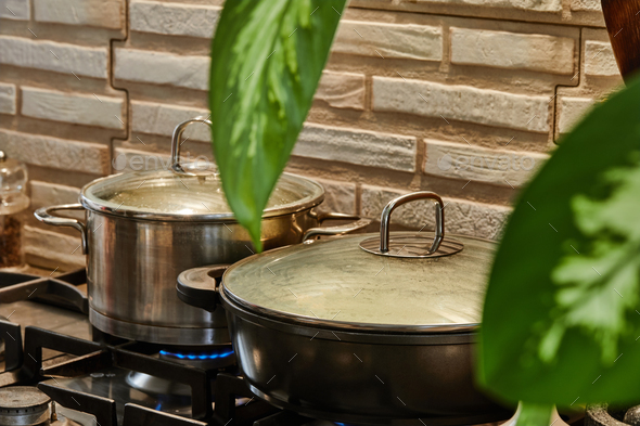 Saucepan and frying pan standing on gas stove while cooking in the ...