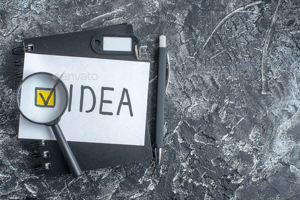 top view black copybook with magnifier and idea note on gray background ...