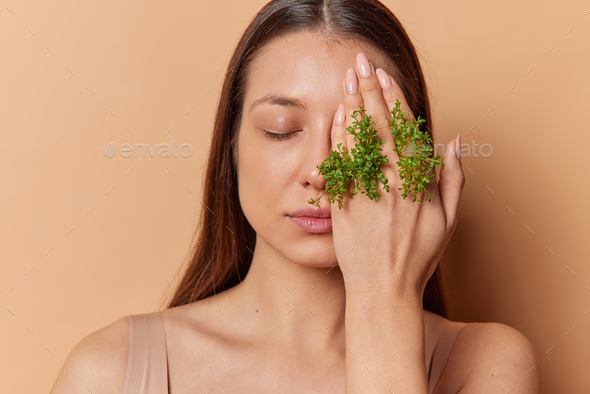 Horizontal shot of dark haired European woman covers half of face keeps ...