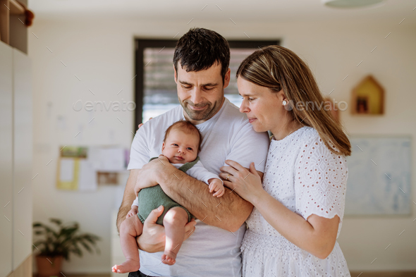 Happy parents cuddling with their newborn baby. Stock Photo by halfpoint