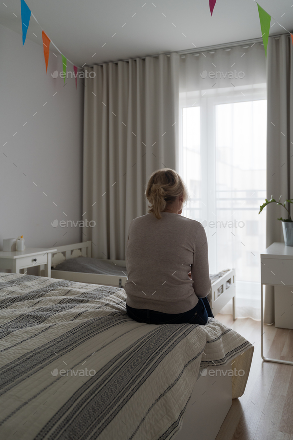 Mature woman sitting alone in the room, sad depressed person. Back view ...
