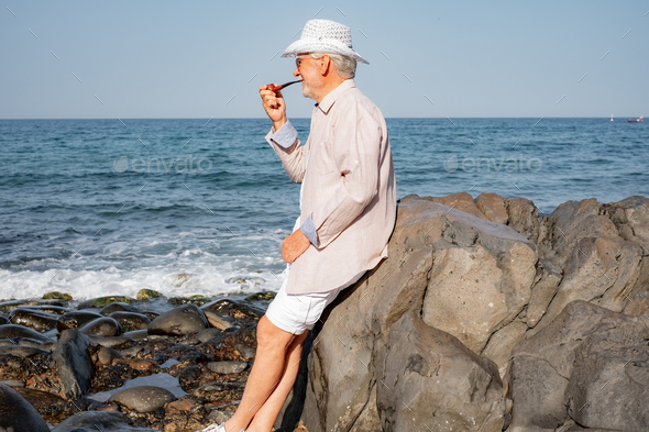 Cheerful Senior Man Standing at the Beach Looking Away Smoking Pipe ...