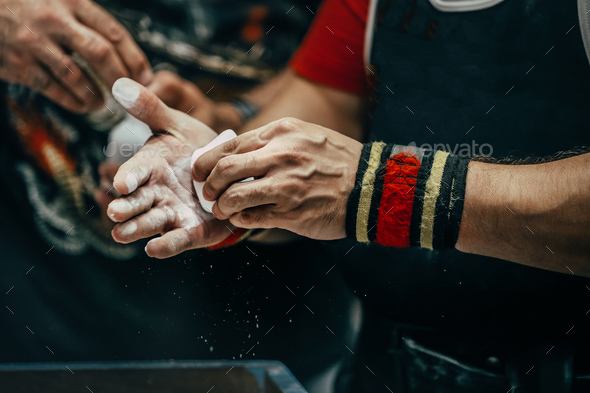 male powerlifter applying gym chalk on his hands before bench press ...