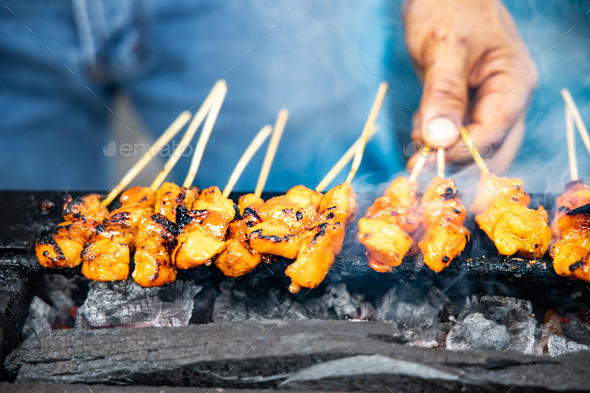 Closeup of chicken satay being barbecue with traditional pit and fired ...