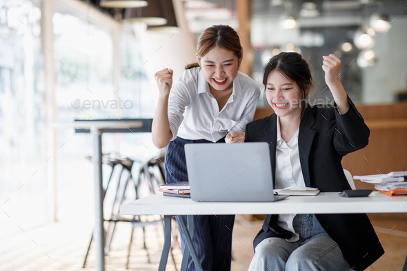 Euphoric winner watching a laptop on a desk winning at working in an ...