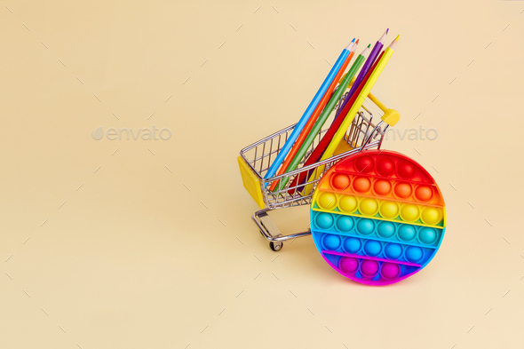 The popular game Pop it and colour pencils in a supermarket cart on a ...