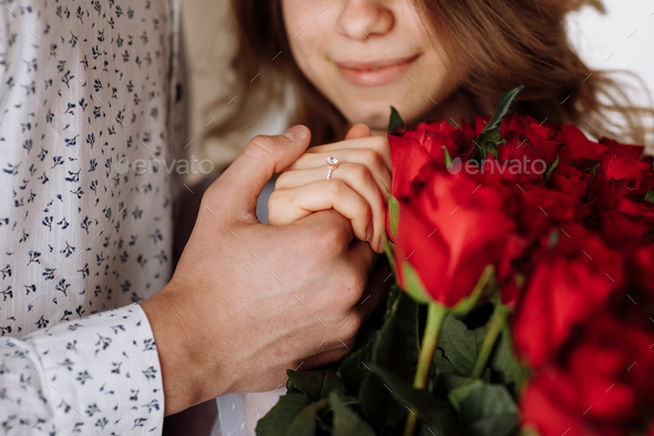young man holding his fiance's hand with gold ring while making a ...