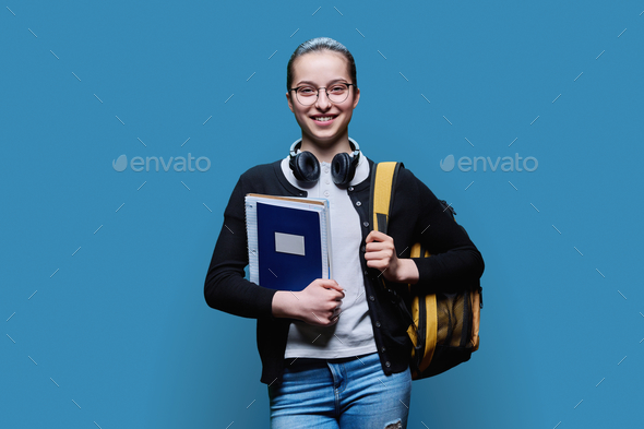 Portrait of teen girl high school student on blue studio background ...