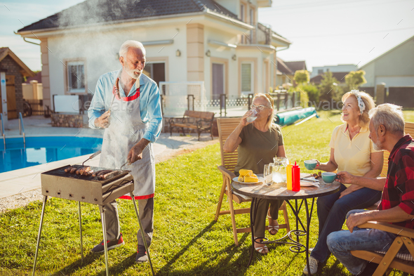 Elderly neighbors having backyard barbecue party by the pool Stock ...