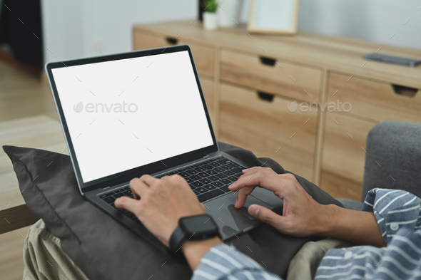 Close up view of man typing on laptop computer with blank white screen ...