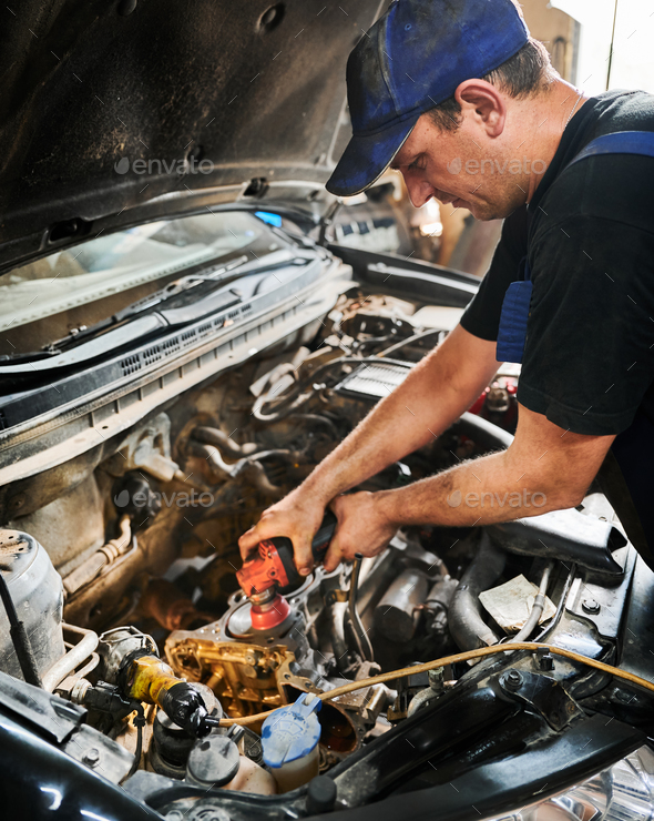 Worker, repairman, mechanic wearing cap and uniform, repairing car ...