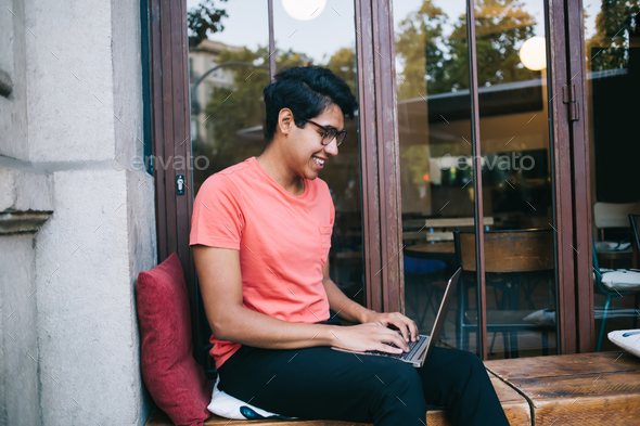 Cheerful Latin guy 20s typing text message during netbook chatting Stock Photo by GaudiLab
