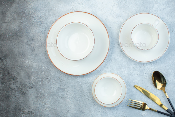 Elegant bright cutlery set and dinnerware set on isolated gray ice ...