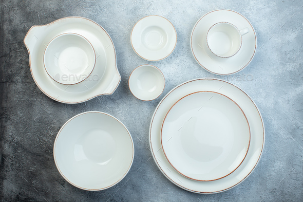 White dinnerware set including many empty plates on half dark light ...