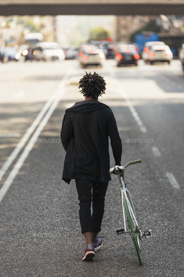 Handsome afro man walking with his bike. Stock Photo by nunezimage