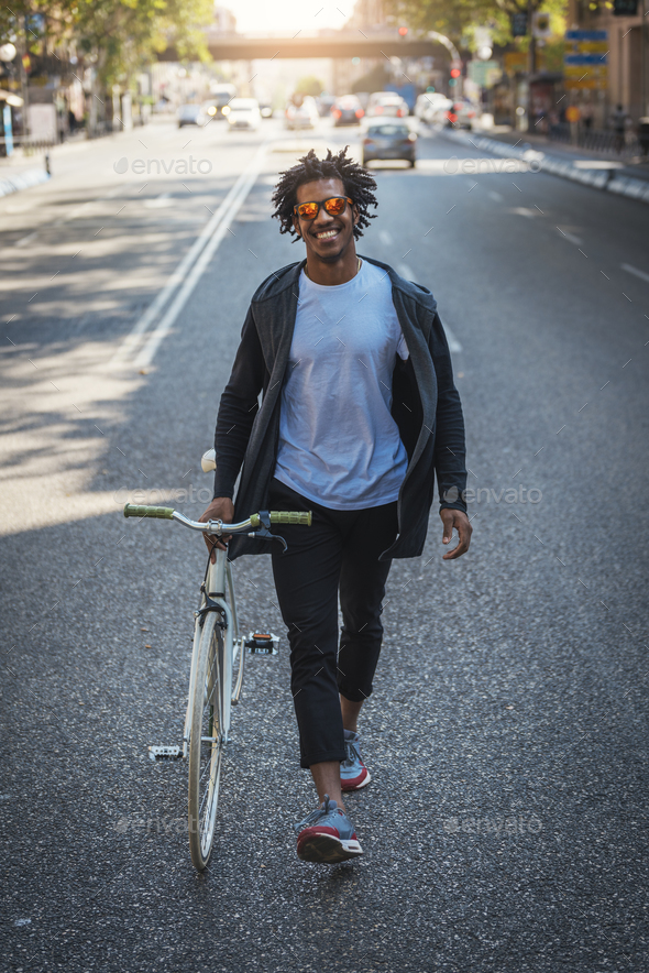 Handsome afro man walking with his bike. Stock Photo by nunezimage