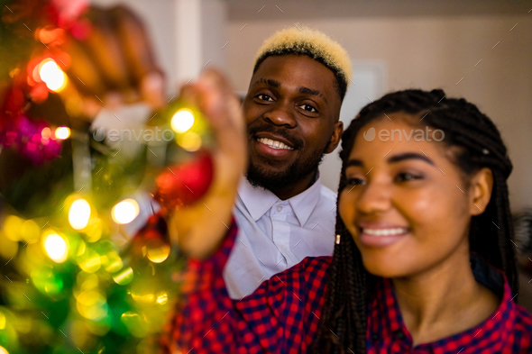 multicultural family decorating christmas tree with ball and garland ...
