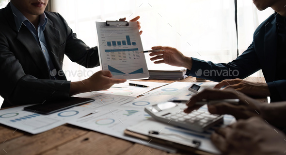 business team discussion of reports displayed in charts and graphs ...
