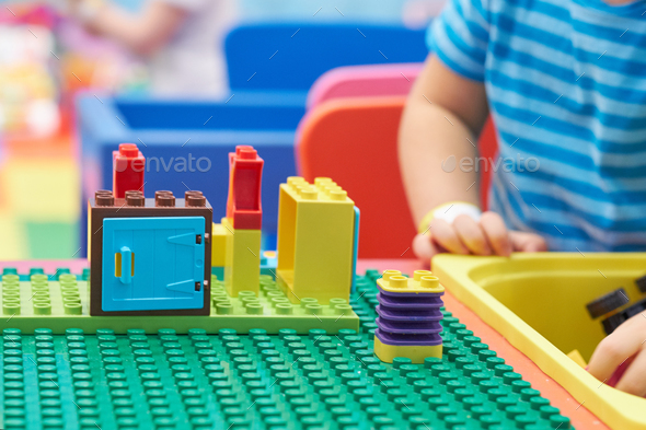child playing and building with colorful plastic bricks table. Early ...
