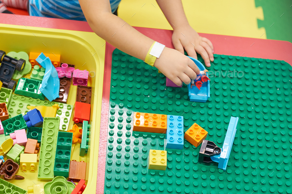 child playing and building with colorful plastic bricks table. Early ...