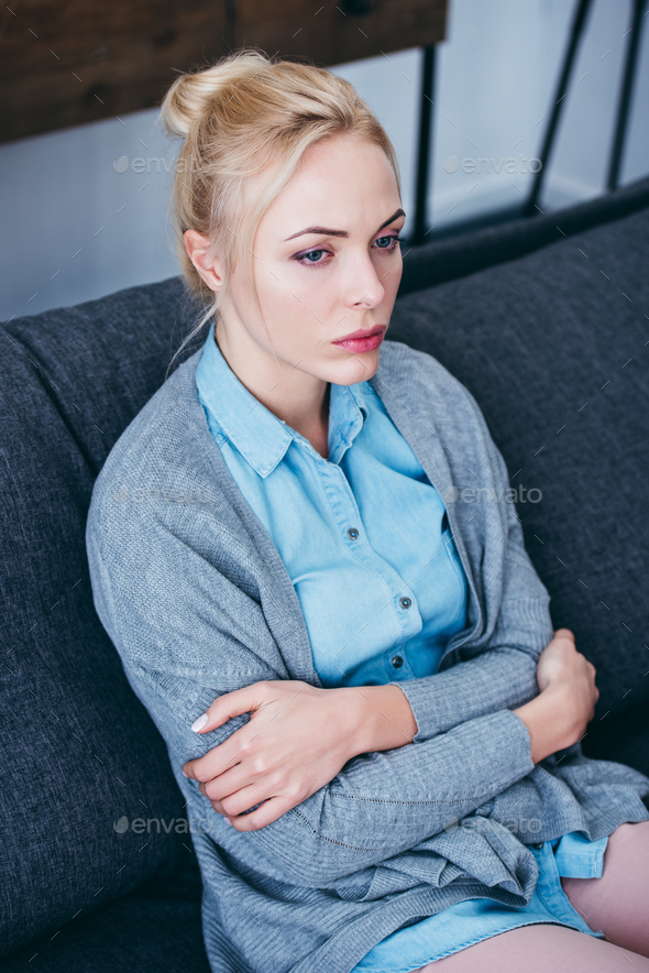 beautiful upset woman with arms crossed sitting on couch at home Stock ...