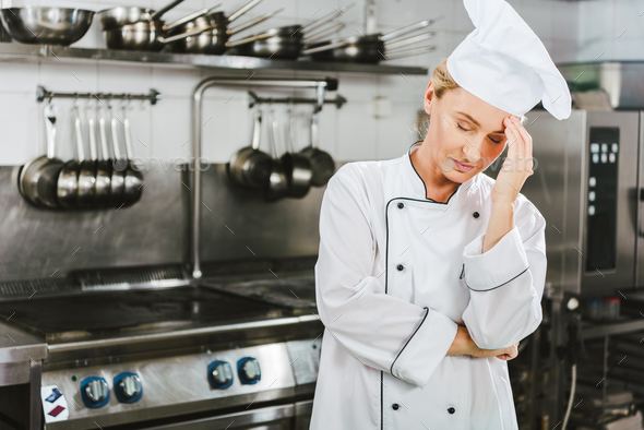 beautiful tired female chef in uniform having headache in restaurant ...