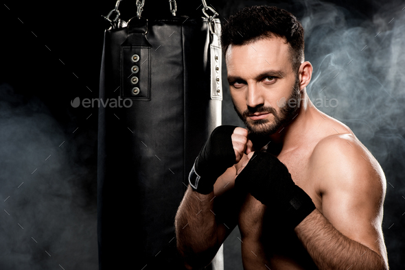 muscular fighter standing in boxing pose and looking at camera near ...