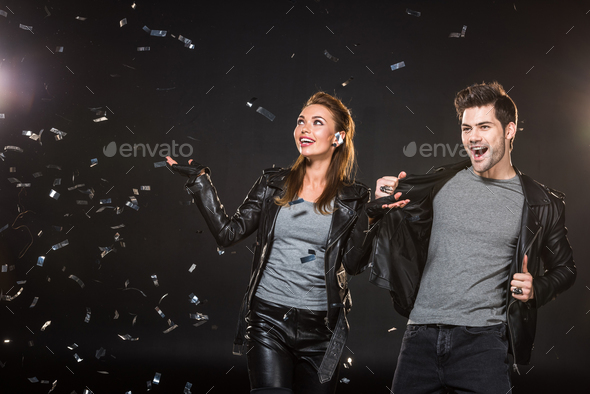 beautiful happy couple in leather jackets cheering with falling ...