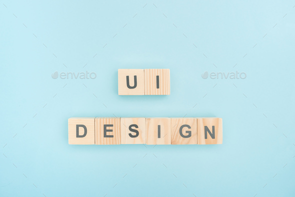 top view of ui design lettering made of wooden cubes on blue background ...