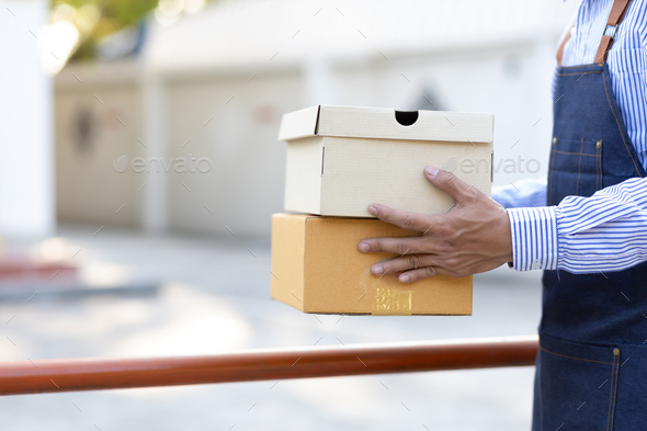 Close-up, the delivery man holding the parcel is handing it to the ...