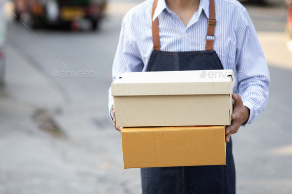 Close-up, the delivery man holding the parcel is handing it to the ...