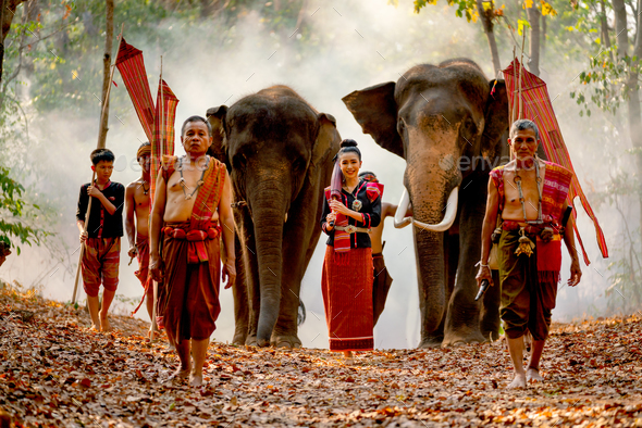Parade of man and woman of mahout village walk along the road in forest ...